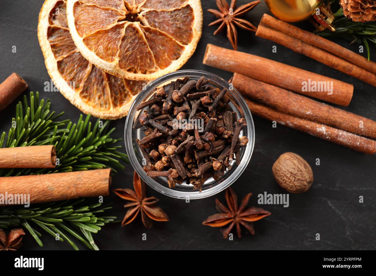 Different aromatic spices and fir tree branches on black table, flat ...
