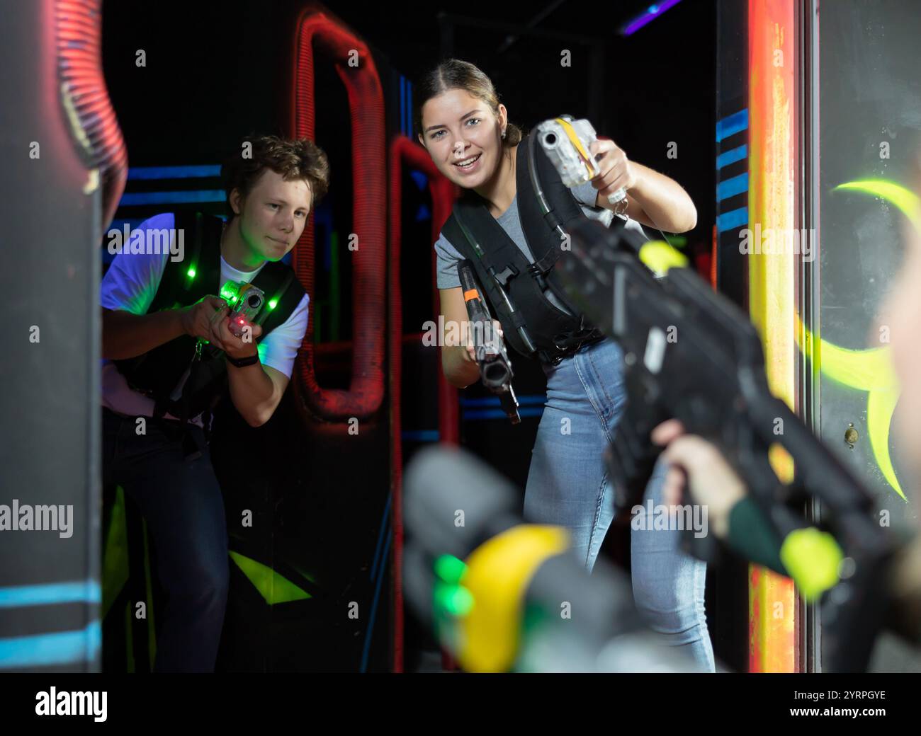 Two players guy and woman with laser weapons in dark laser tag room ...