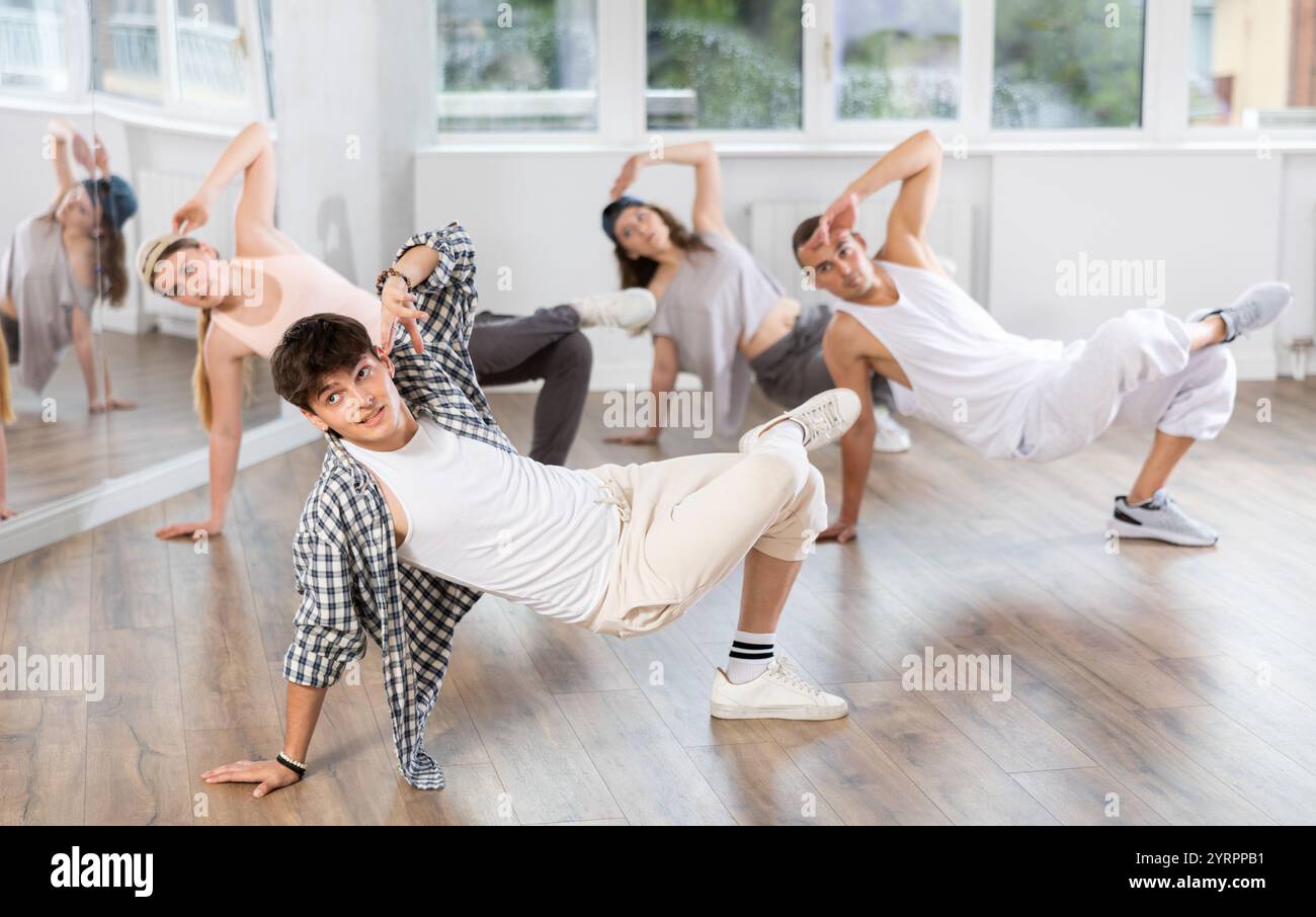 Man and his students perform hip hop dance on one bent leg, movement in ...