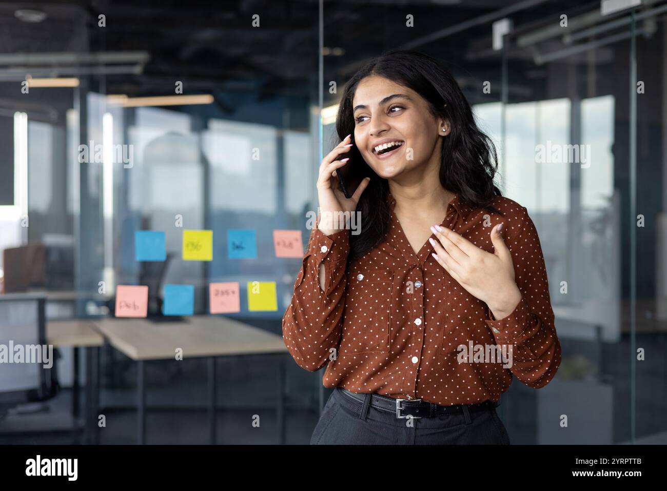 A cheerful businesswoman is engaged in a lively phone conversation in a ...