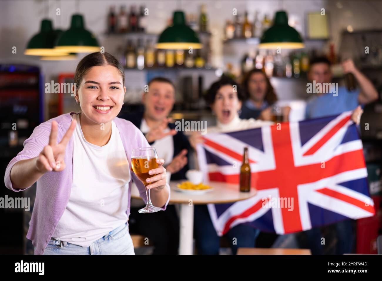 Happy young adult fans waving British flag while drinking beer and ...