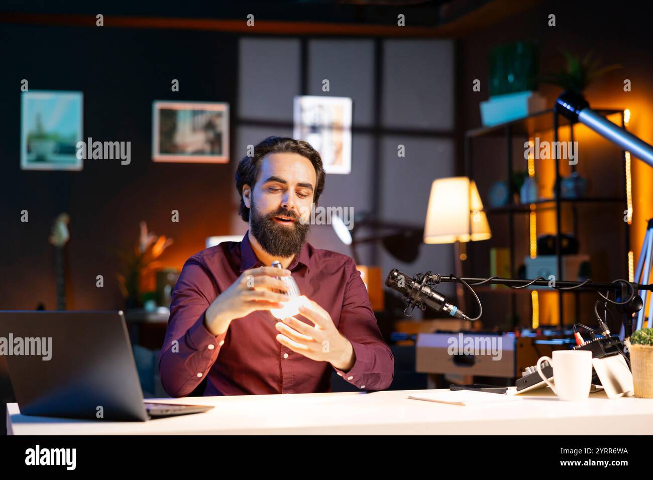 Influencer in dimly lit apartment studio filming smart light bulb ...