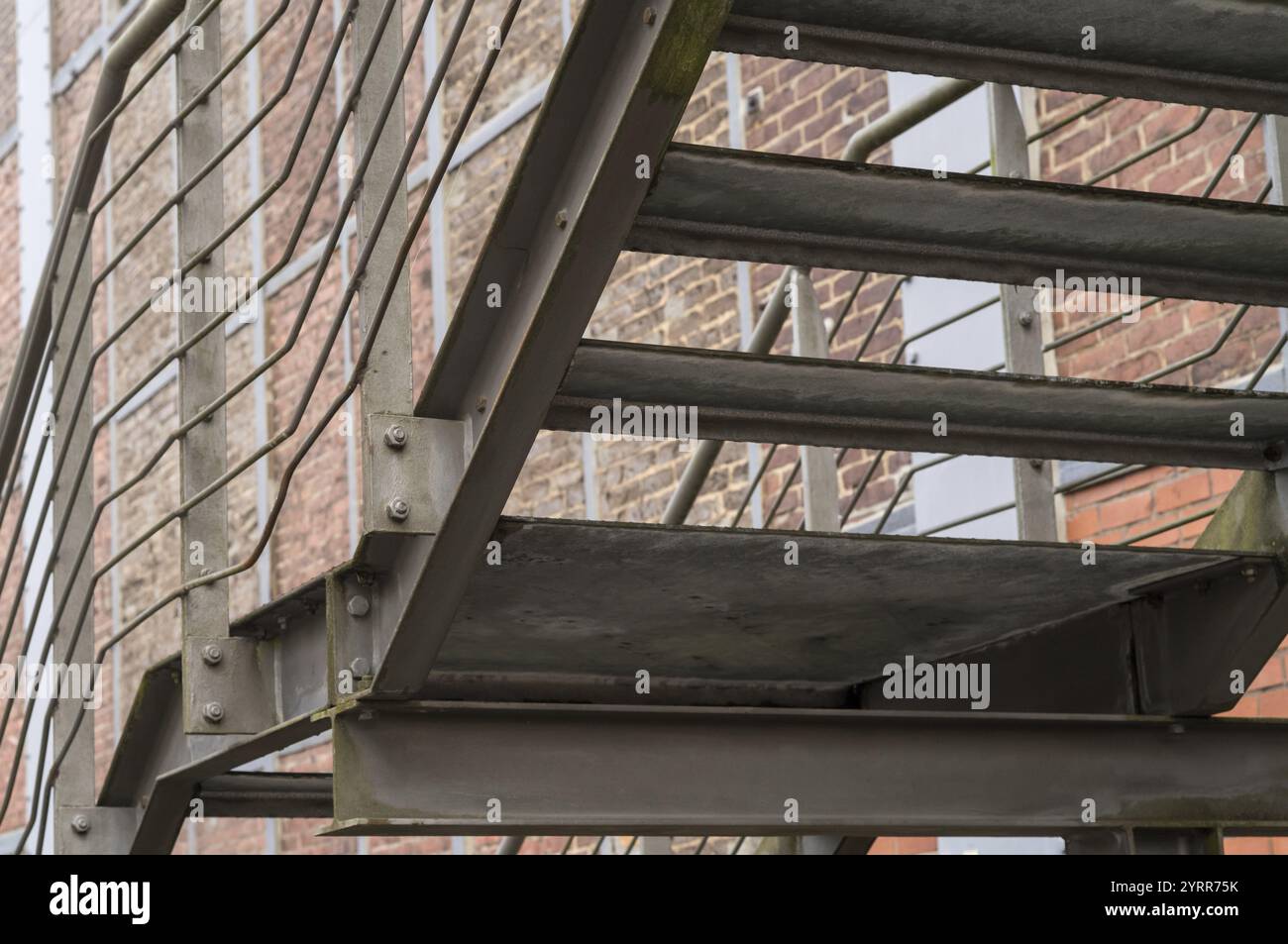 Metal fire escape with caged mesh wire alongside red brick building ...