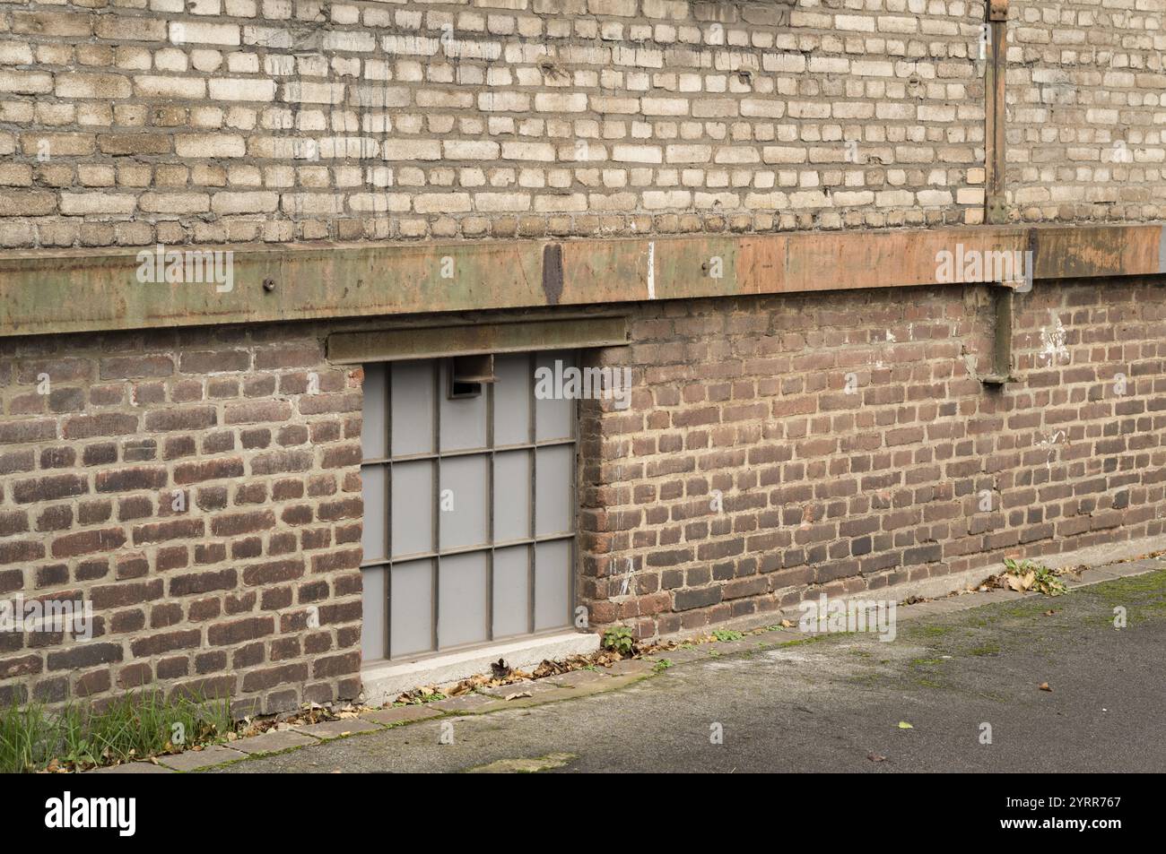 Frosted glass basement window illuminating a weathered industrial brick ...