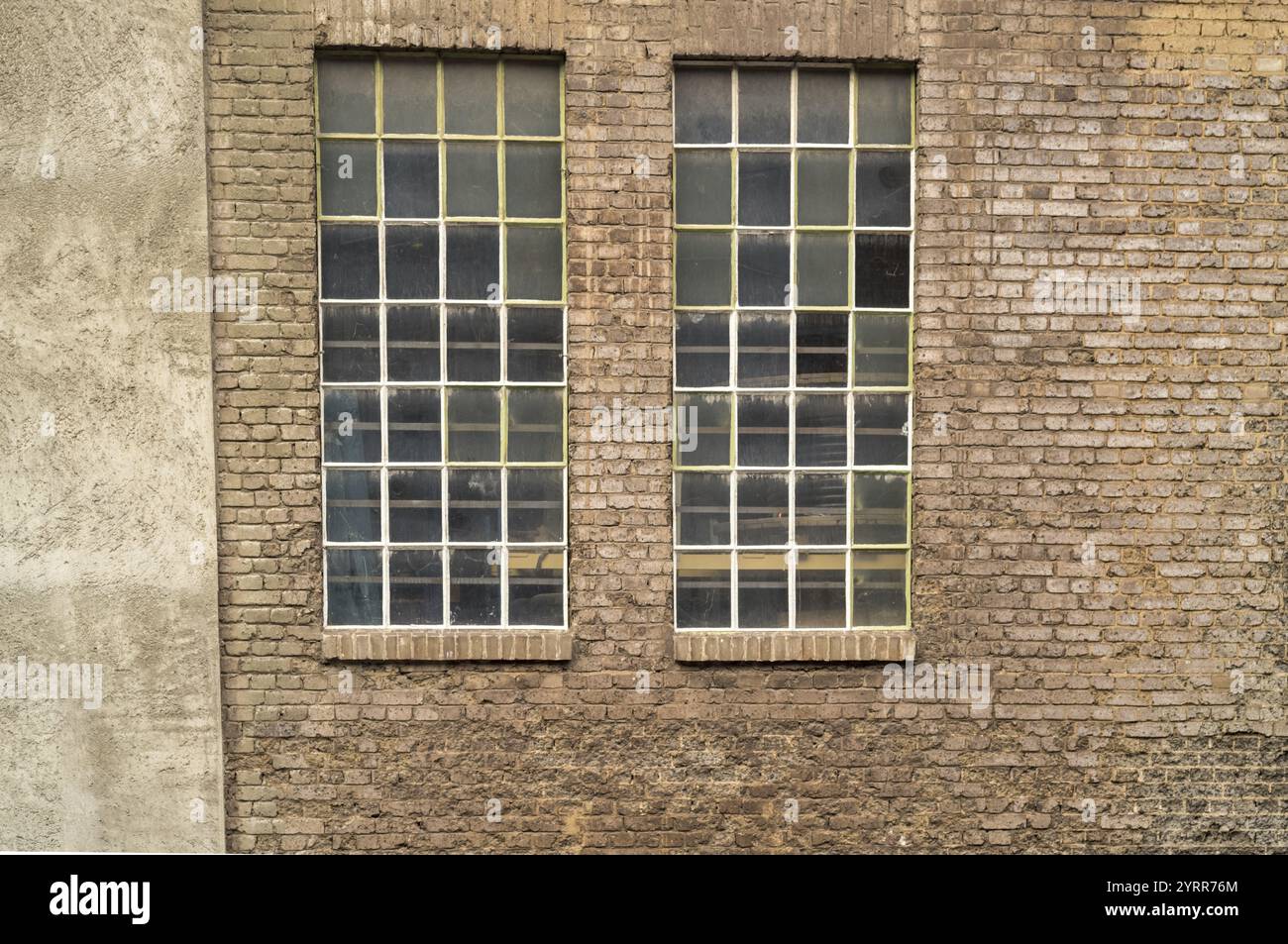 Two large industrial windows with small panes and metal bars are set in ...