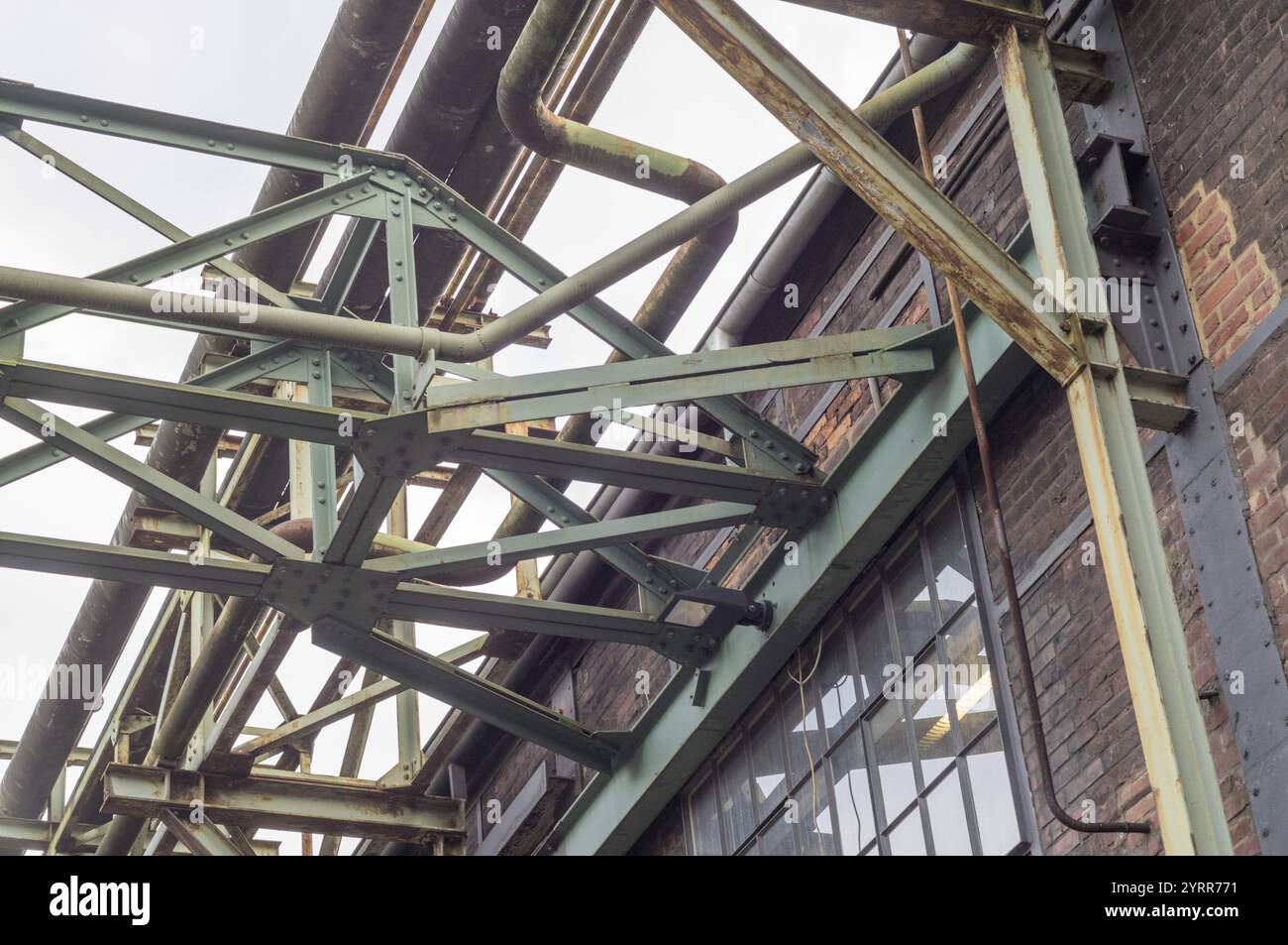 Metal framework supporting pipelines on an old brick wall in an ...