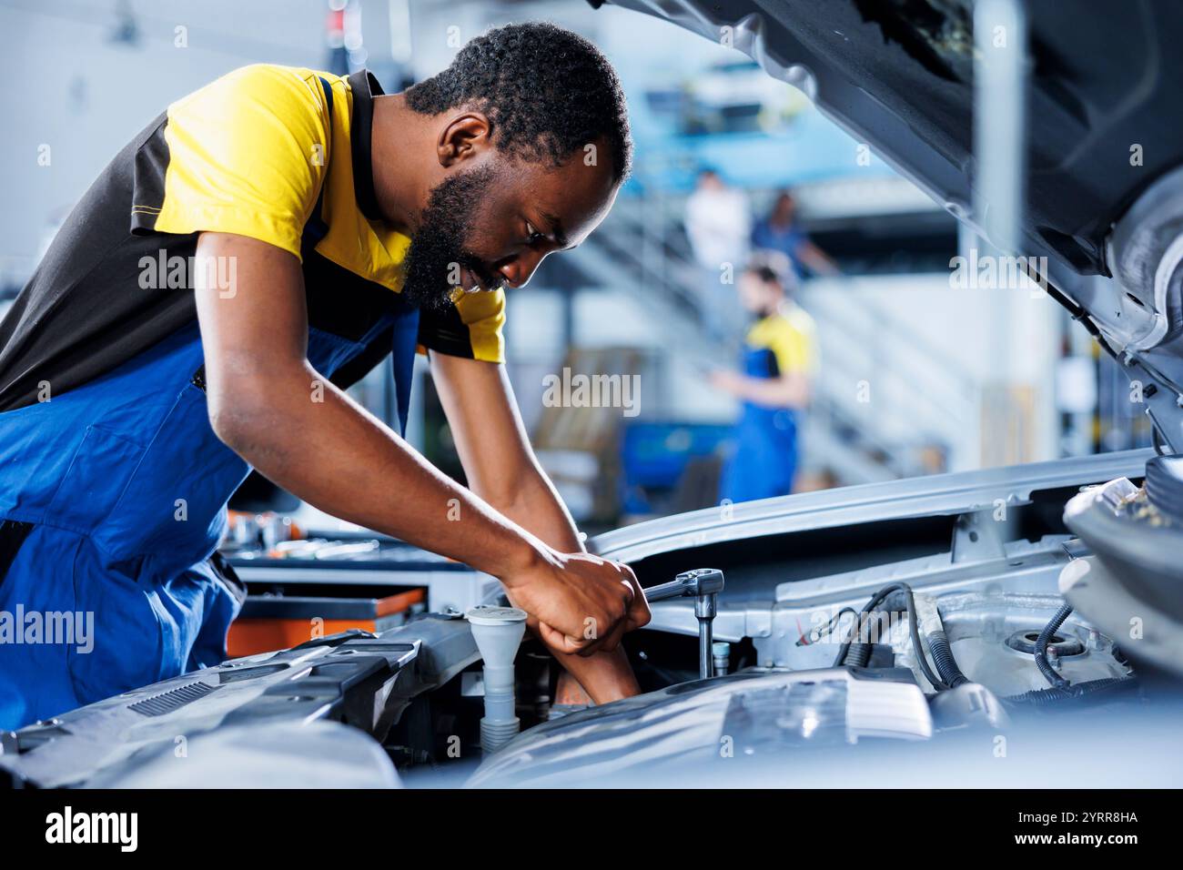 African american repairman in car service uses torque wrench to tighten ...