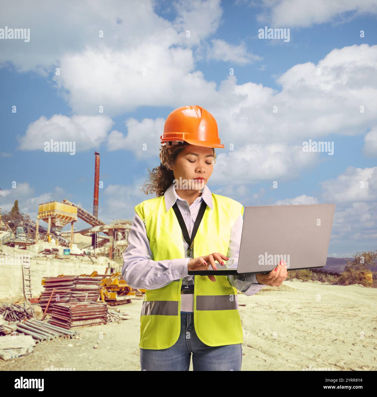 Female asian engineer using a laptop computer at a construction site ...