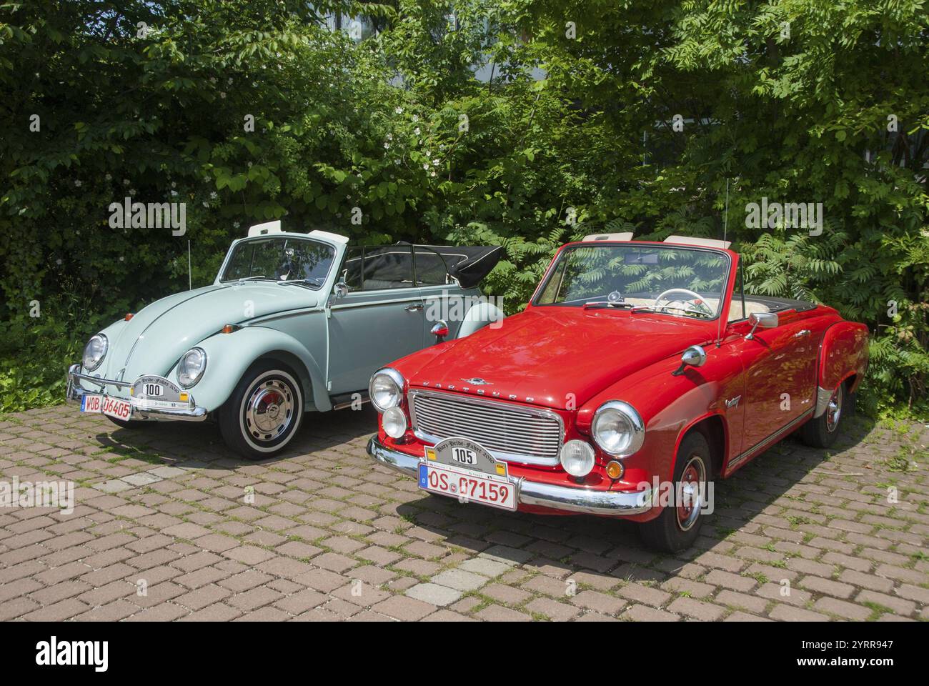 Two classic convertibles, one red and one light blue, parked next to ...