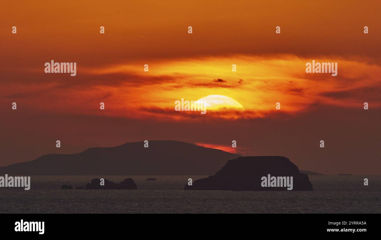 Sun setting behind the horizon, islands in the foreground under a ...