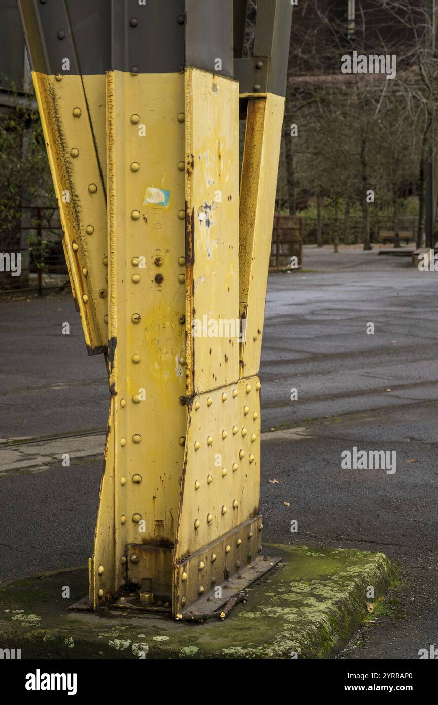 Close-up of a weathered yellow metal pillar, showing rivets and signs ...
