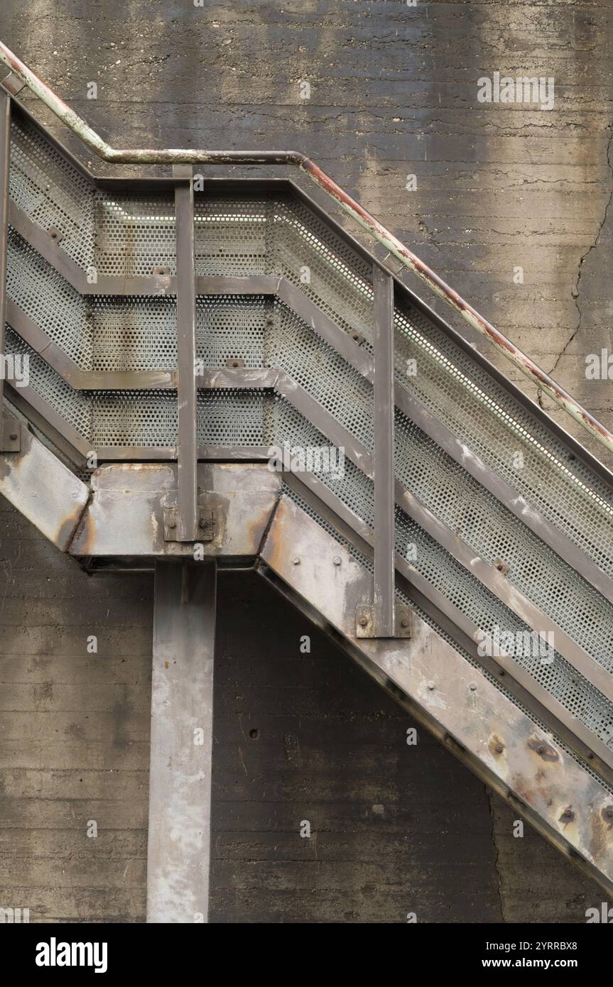 Rusty metal staircase with perforated steps fixed to a concrete wall ...