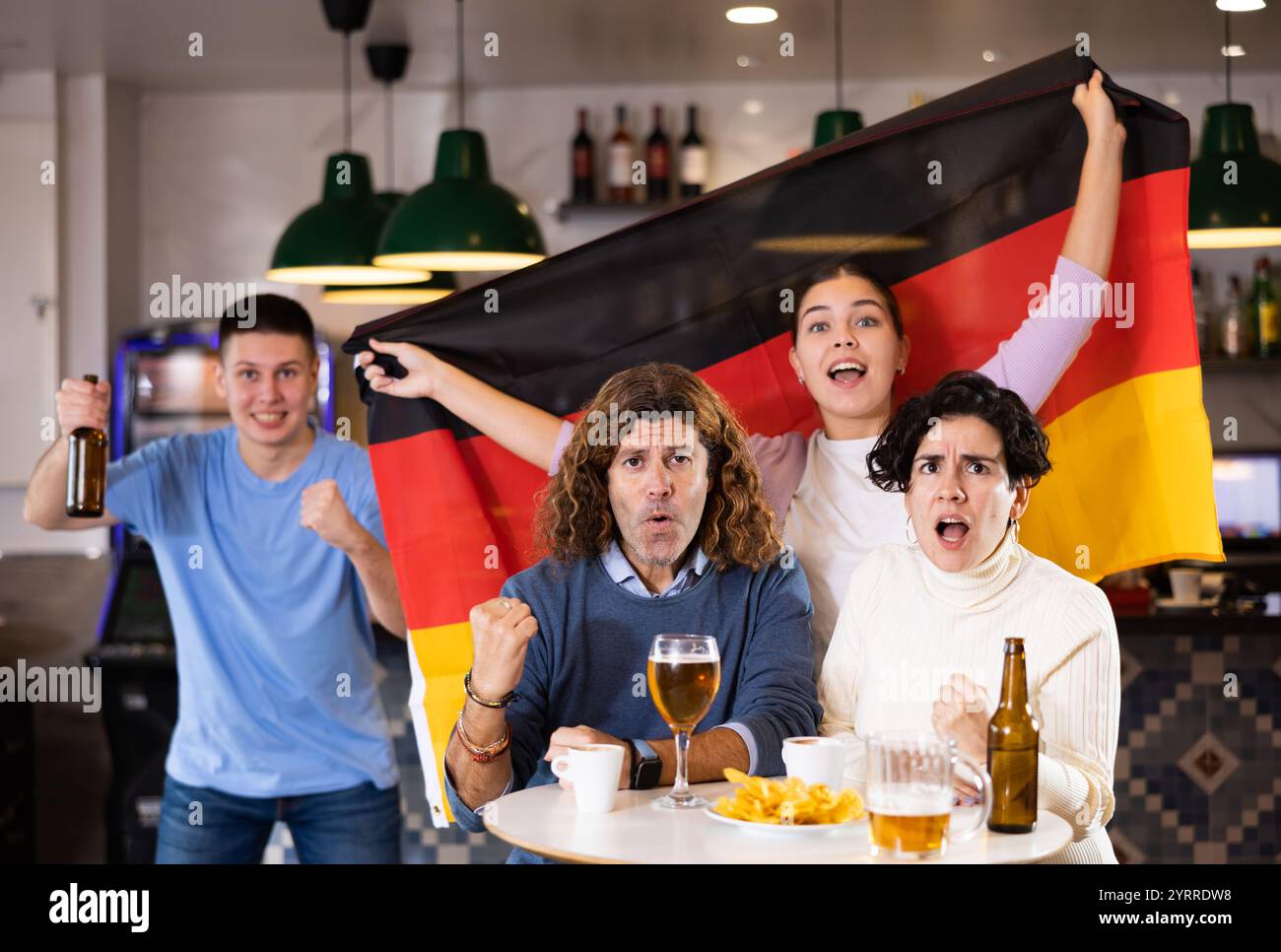 Company of screaming young adult sports fans waving flag of Germany and ...