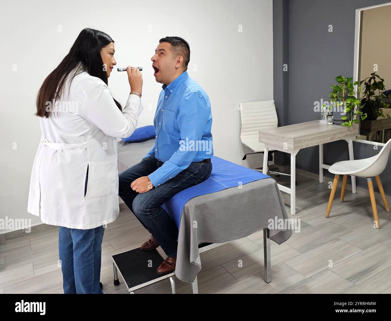 Latina female doctor checks dark-skinned male patient in office for ...