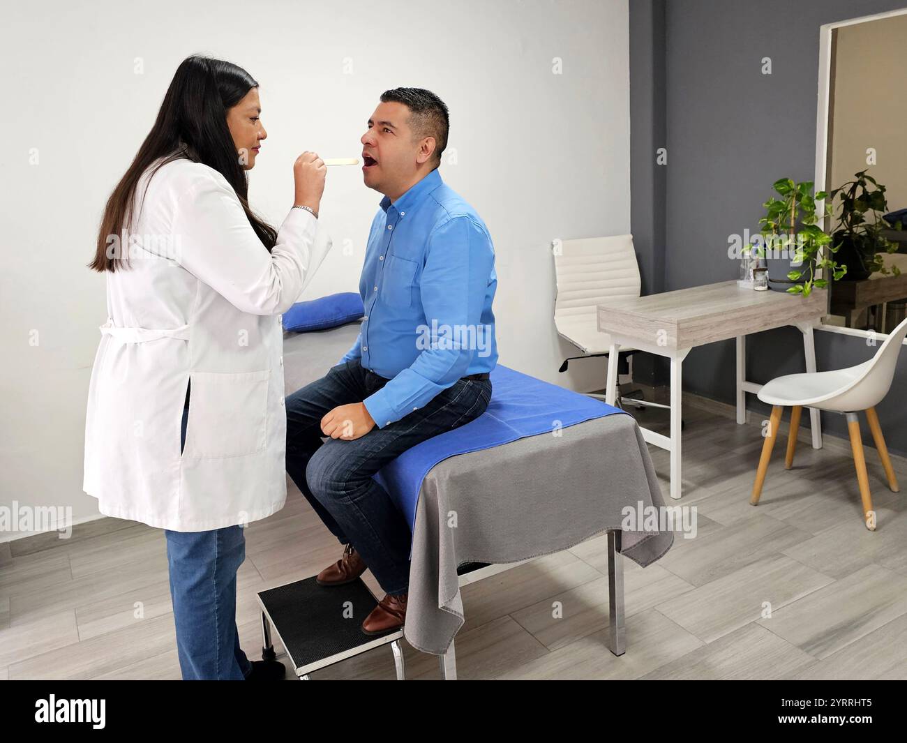 Latina female doctor checks dark-skinned male patient in office for ...