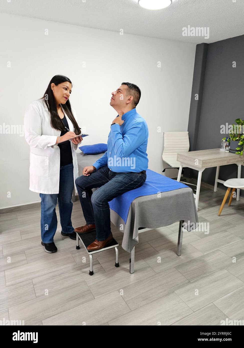 Latina female doctor checks dark-skinned male patient in office for ...
