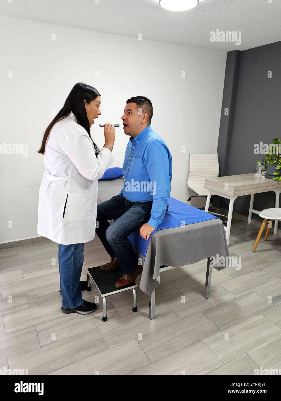 Latina female doctor checks dark-skinned male patient in office for ...