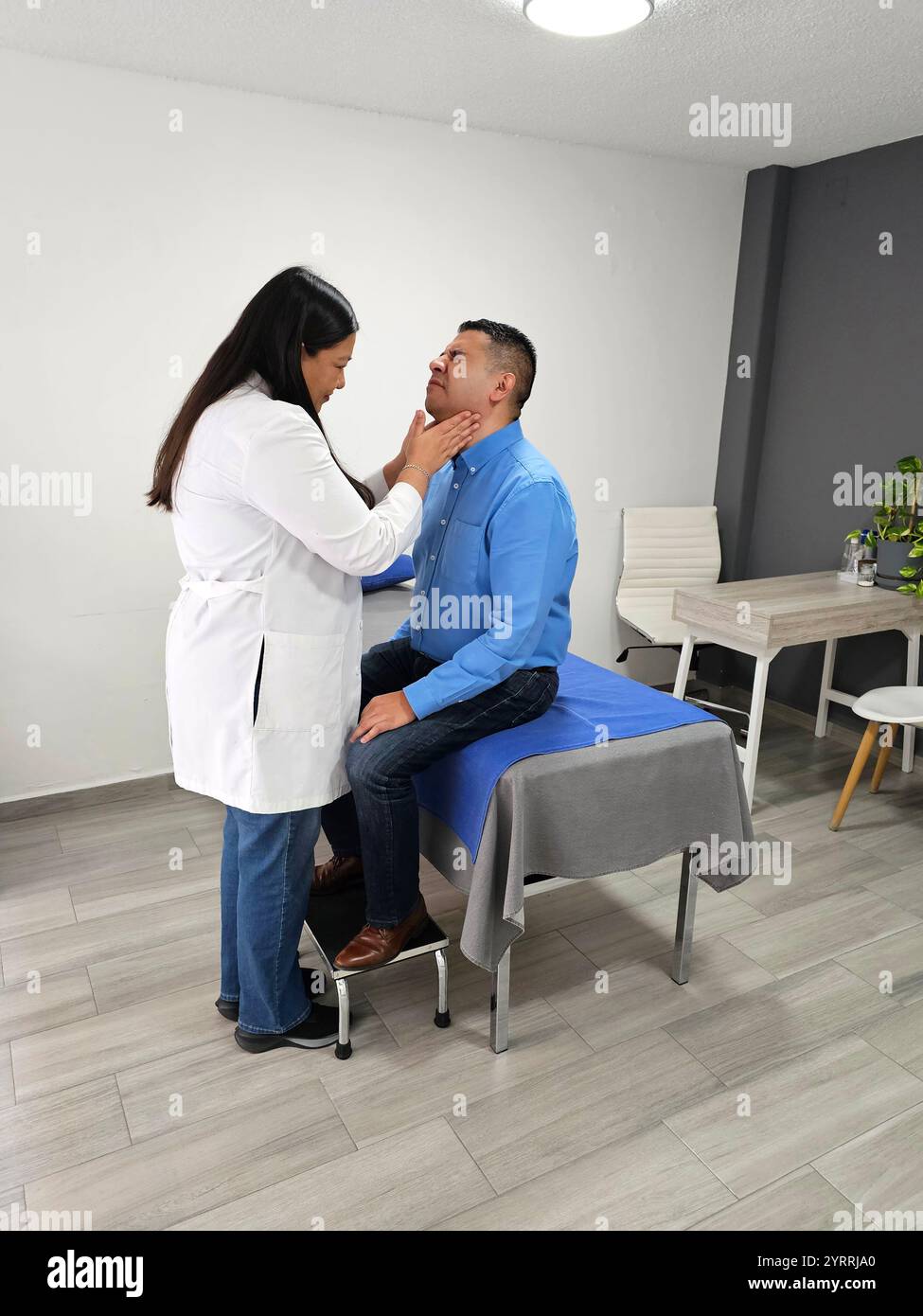 Latina female doctor checks dark-skinned male patient in office for ...