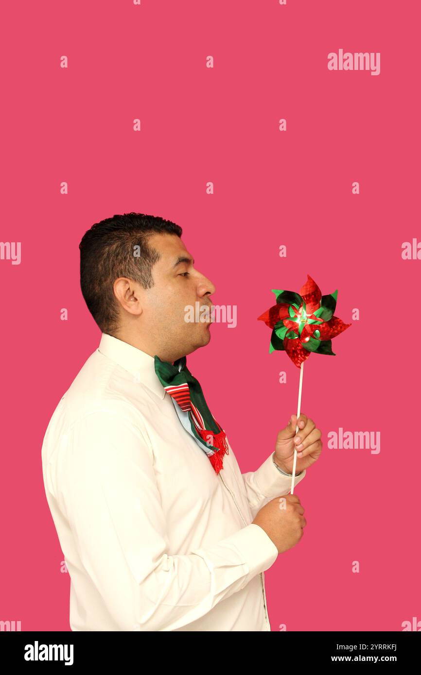 40-year-old dark-skinned Mexican man blows to spin a tricolor pinwheel ...