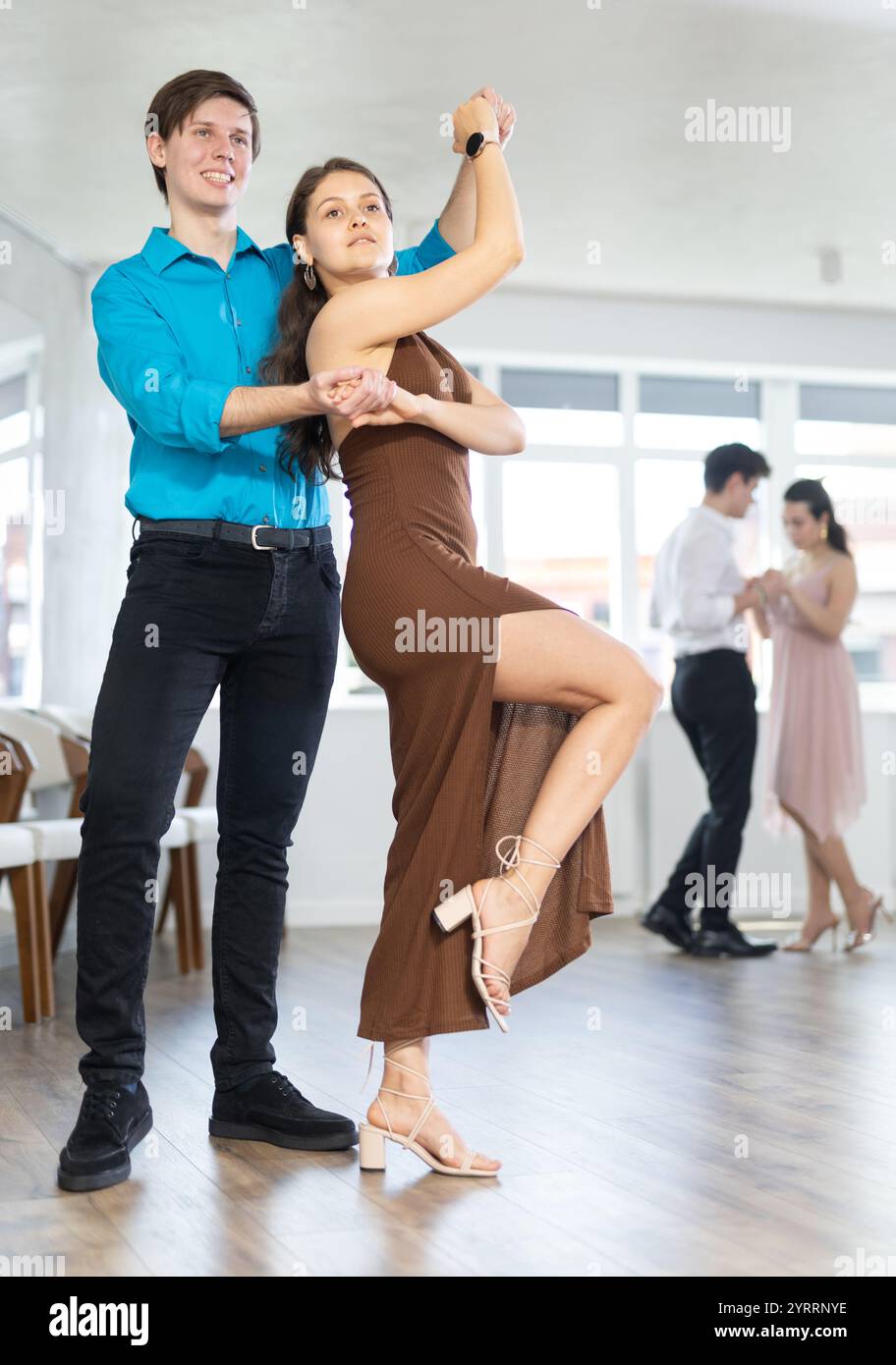 Young couples learning to dance latin american dances in dance studio ...