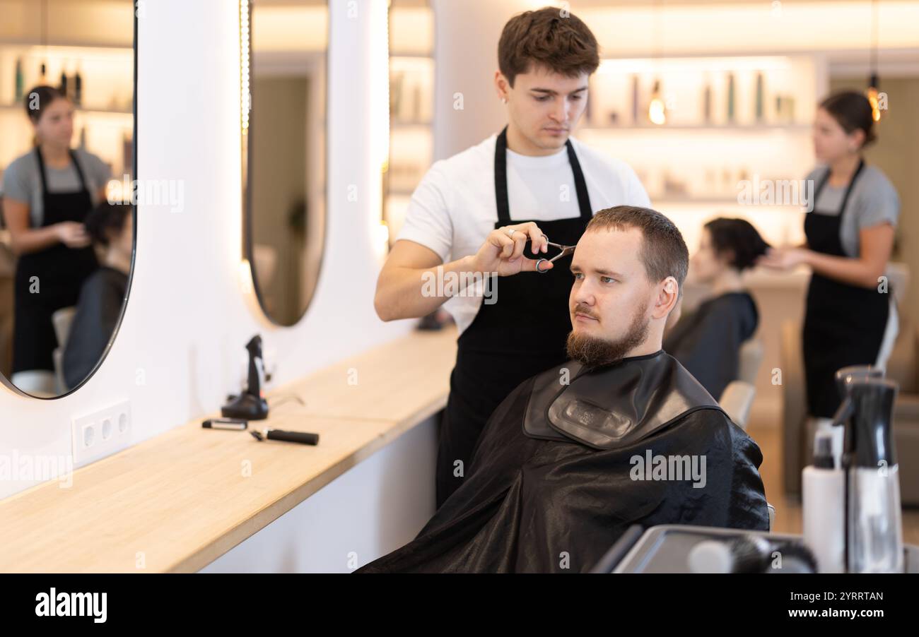 Young guy hairdresser giving haircut to young man Stock Photo - Alamy