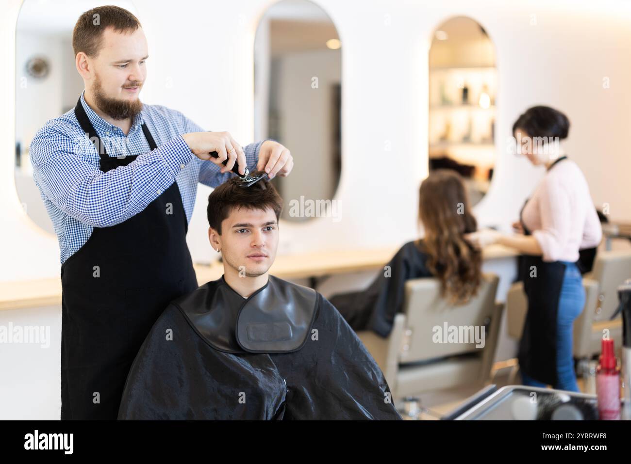 Young male hairdresser giving haircut to young guy Stock Photo - Alamy