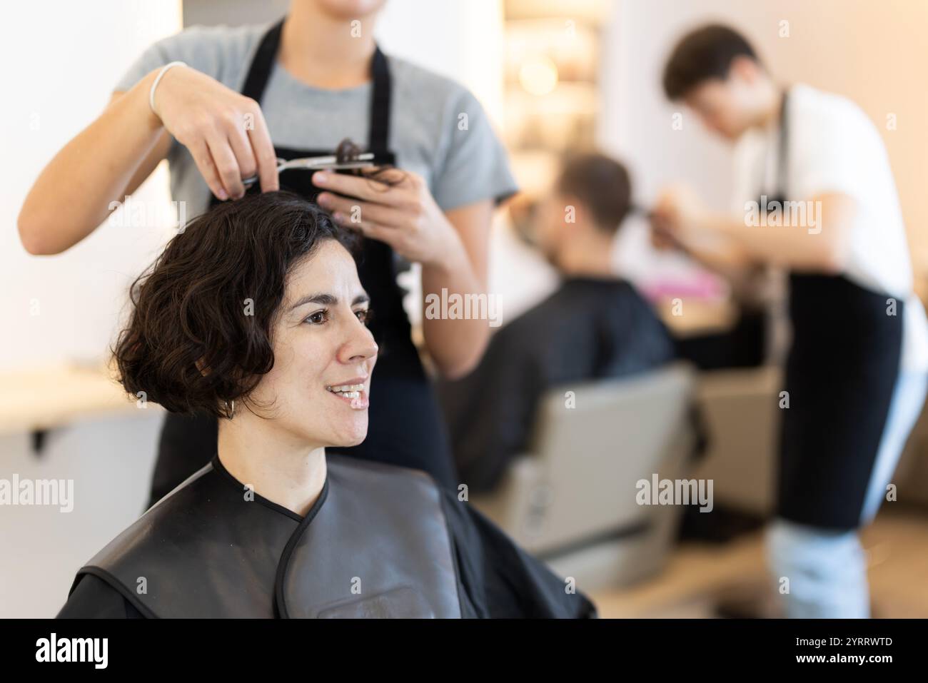 Female hairdresser giving haircut to adult woman Stock Photo - Alamy