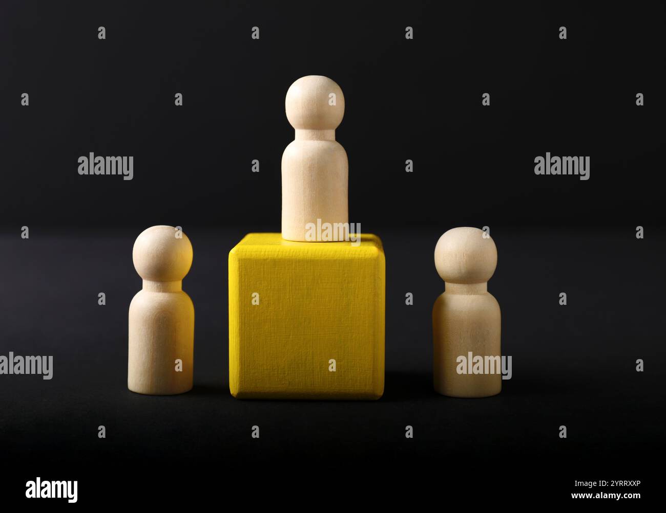 Winner. One wooden figure on podium among others against black ...