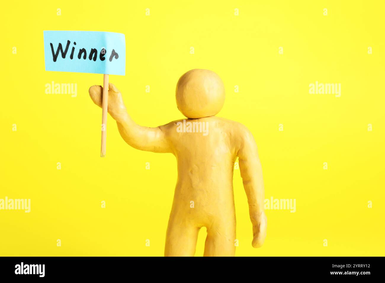 Human figure holding wooden stick with word Winner on yellow background ...