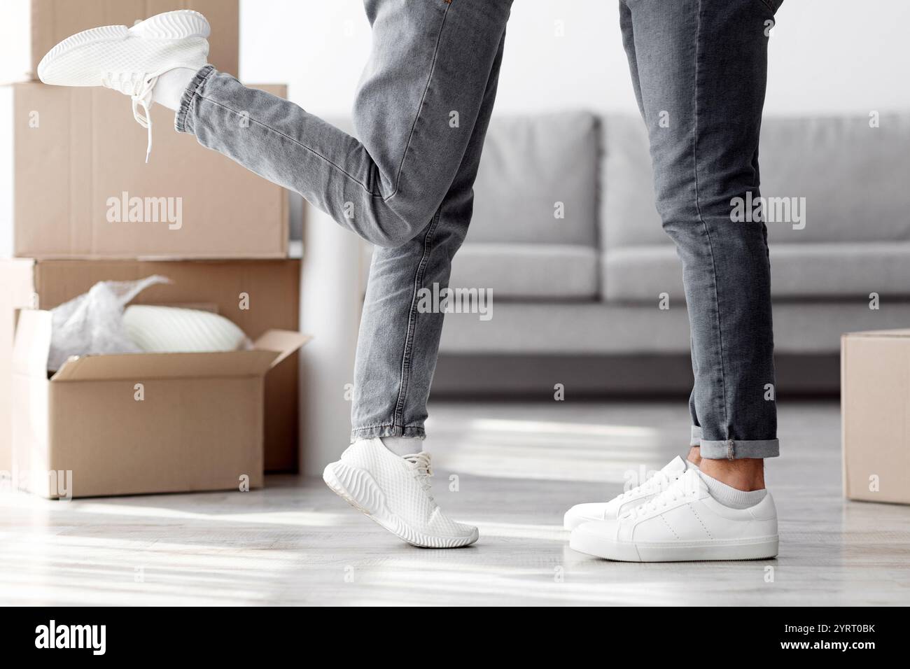 Legs of hugging man and woman standing among moving boxes Stock Photo ...