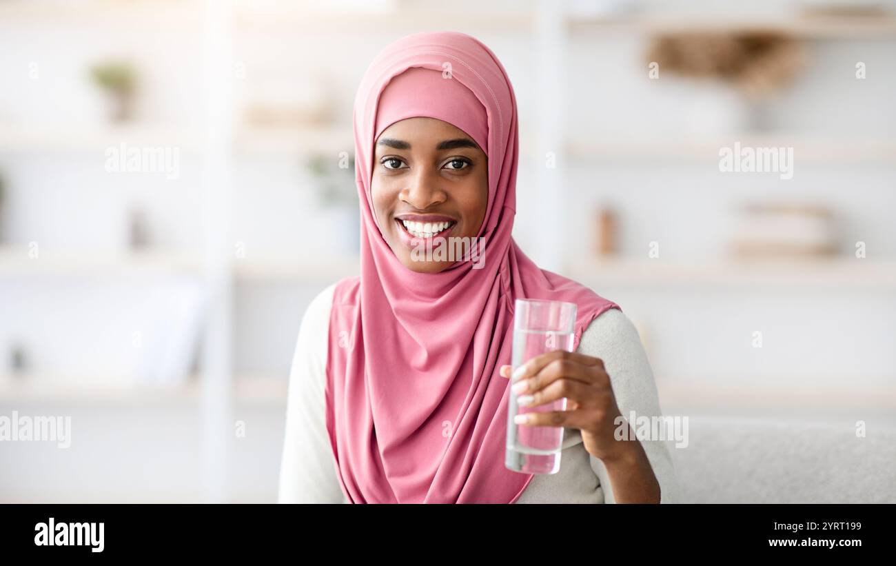 Smiling Black Muslim Lady In Hijab Drinking Water From Glass At Home ...
