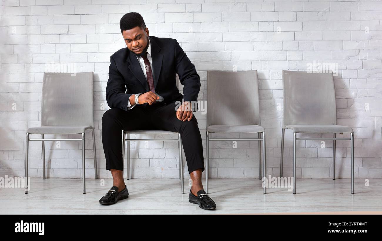 Millennial African American guy waiting for job interview, looking at ...