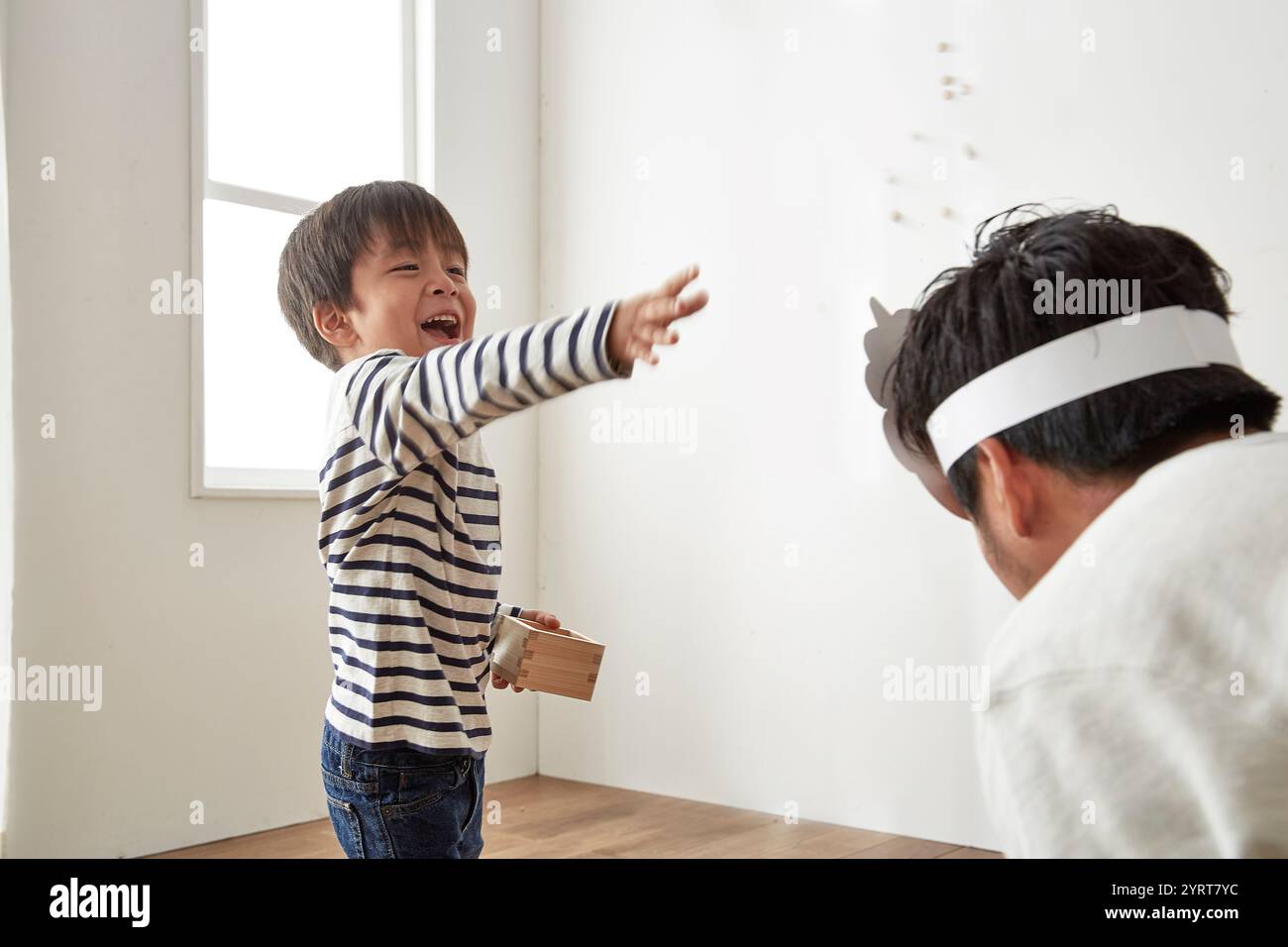 A boy throwing beans at his father who is playing the role of the demon ...