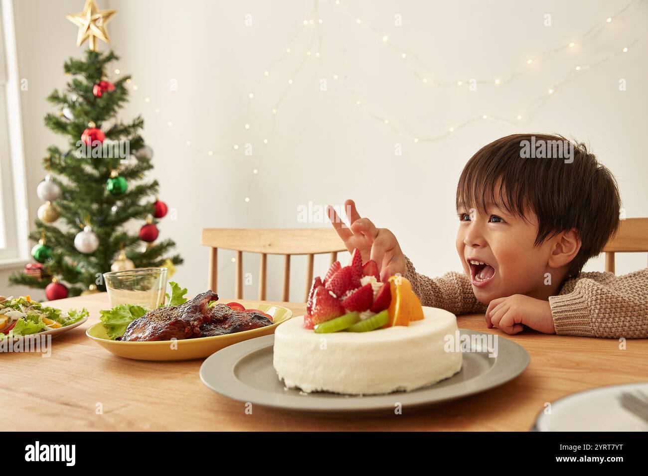 Boy laughing as he tries to pick up and eat a piece of cake Stock Photo ...
