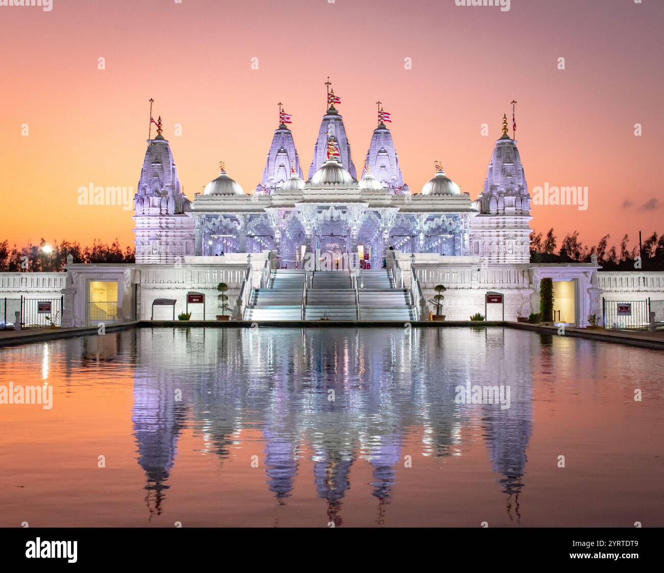 Purple illuminated BAPS Shri Swaminarayan Mandir reflected against ...
