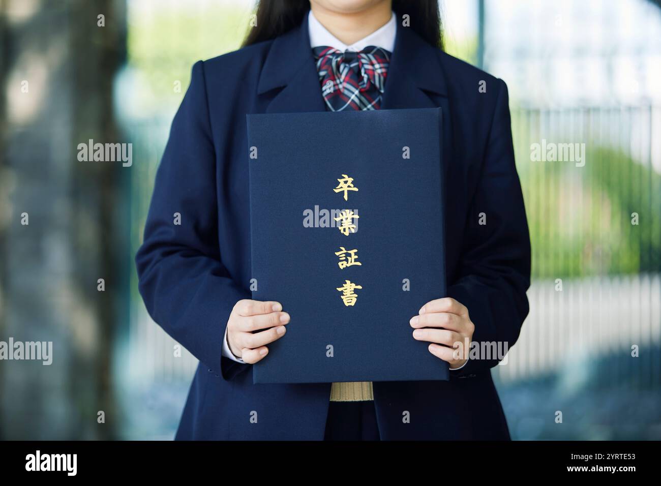 A female student wearing a uniform and holding a diploma Stock Photo ...