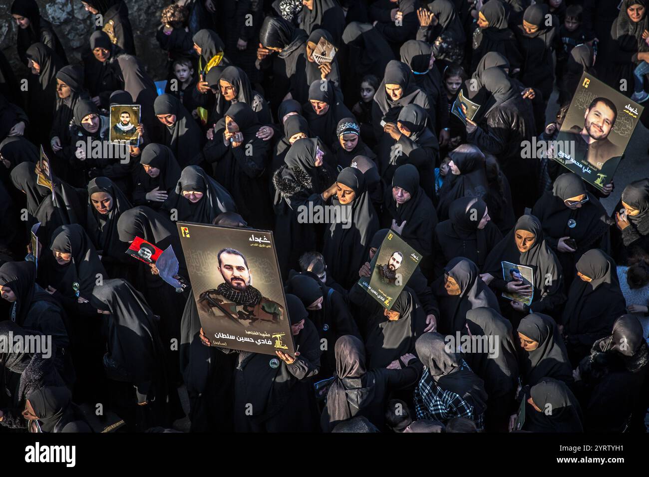Female mourners hold up pictures of Hezbollah fighters killed by Israel ...