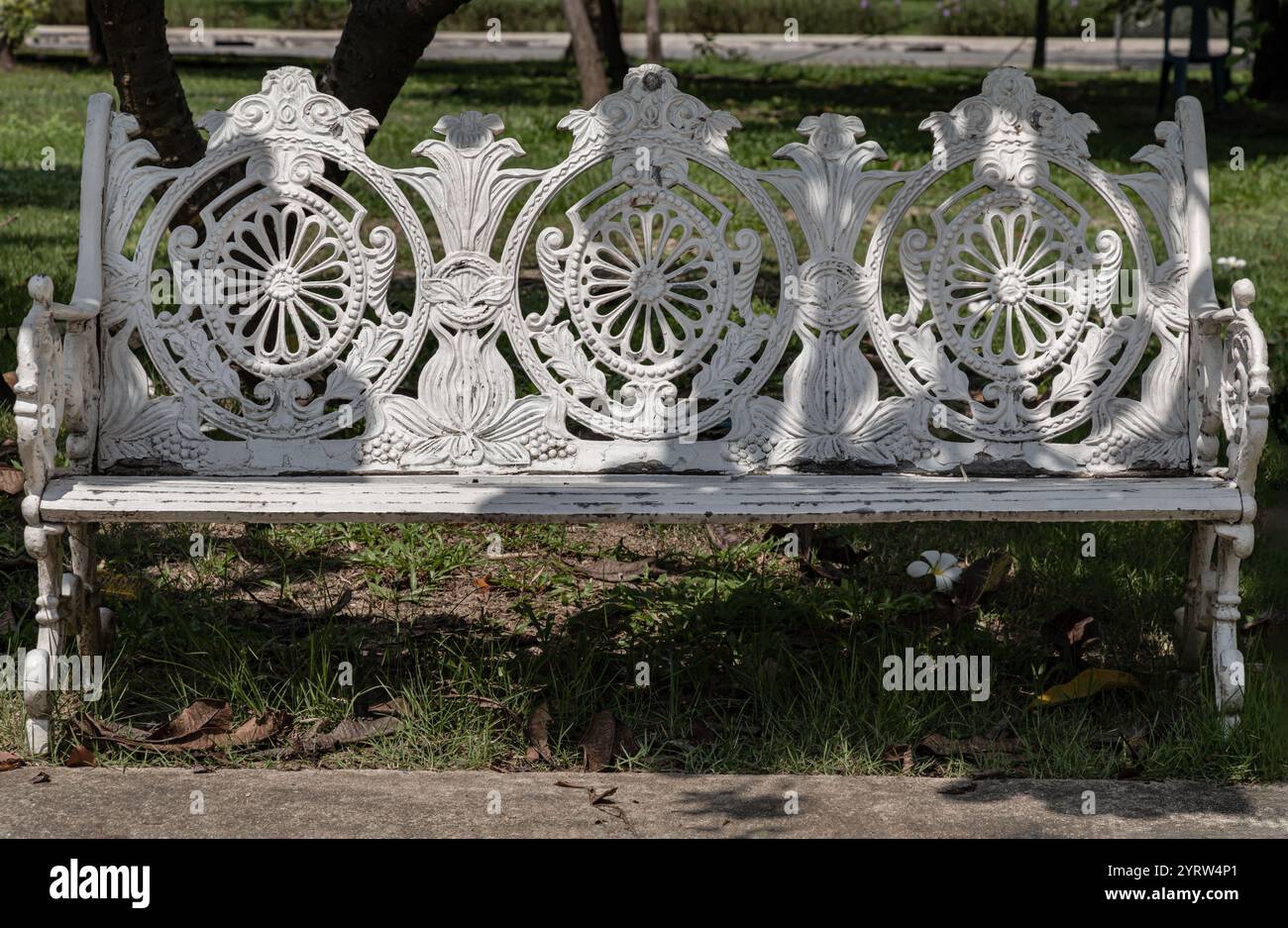 Sunlight on backrest surface of Empty ornate antique cast iron bench in ...