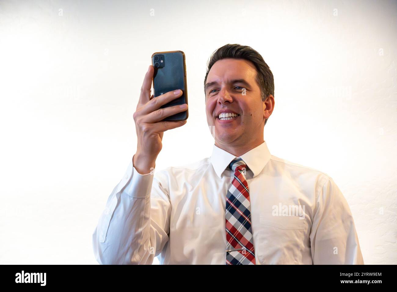 Smiling man captures joyous moment on his smartphone during a bright ...