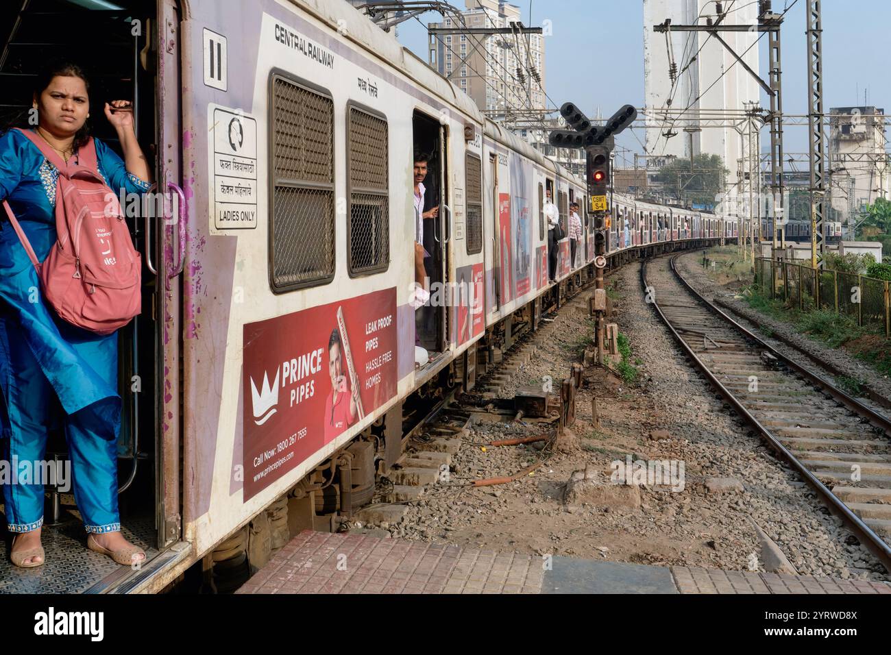 Mumbai, India: A female passenger stands precariously at the open door ...
