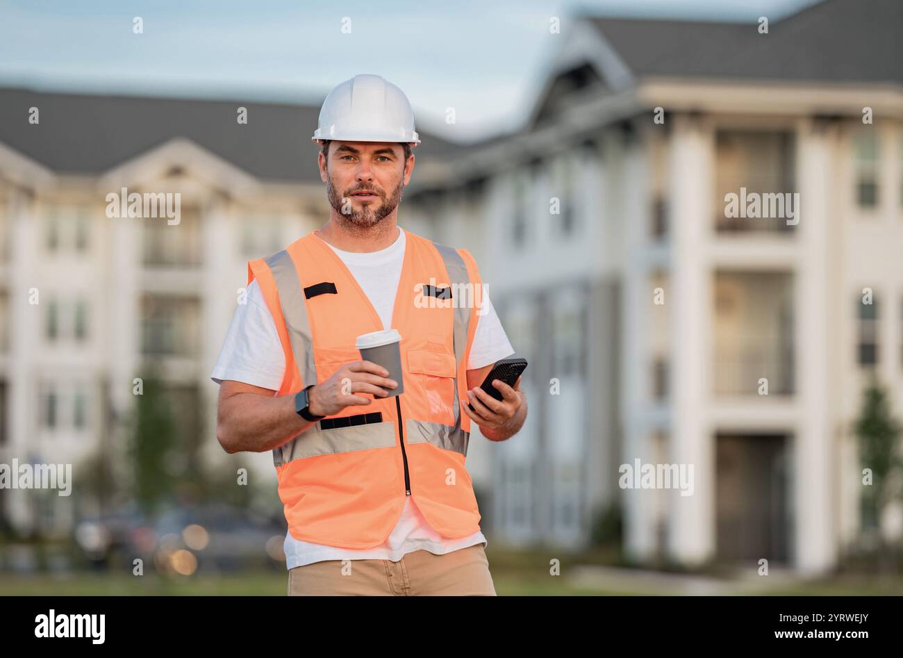 Engineer builder drinking take away coffee using phone on break ...