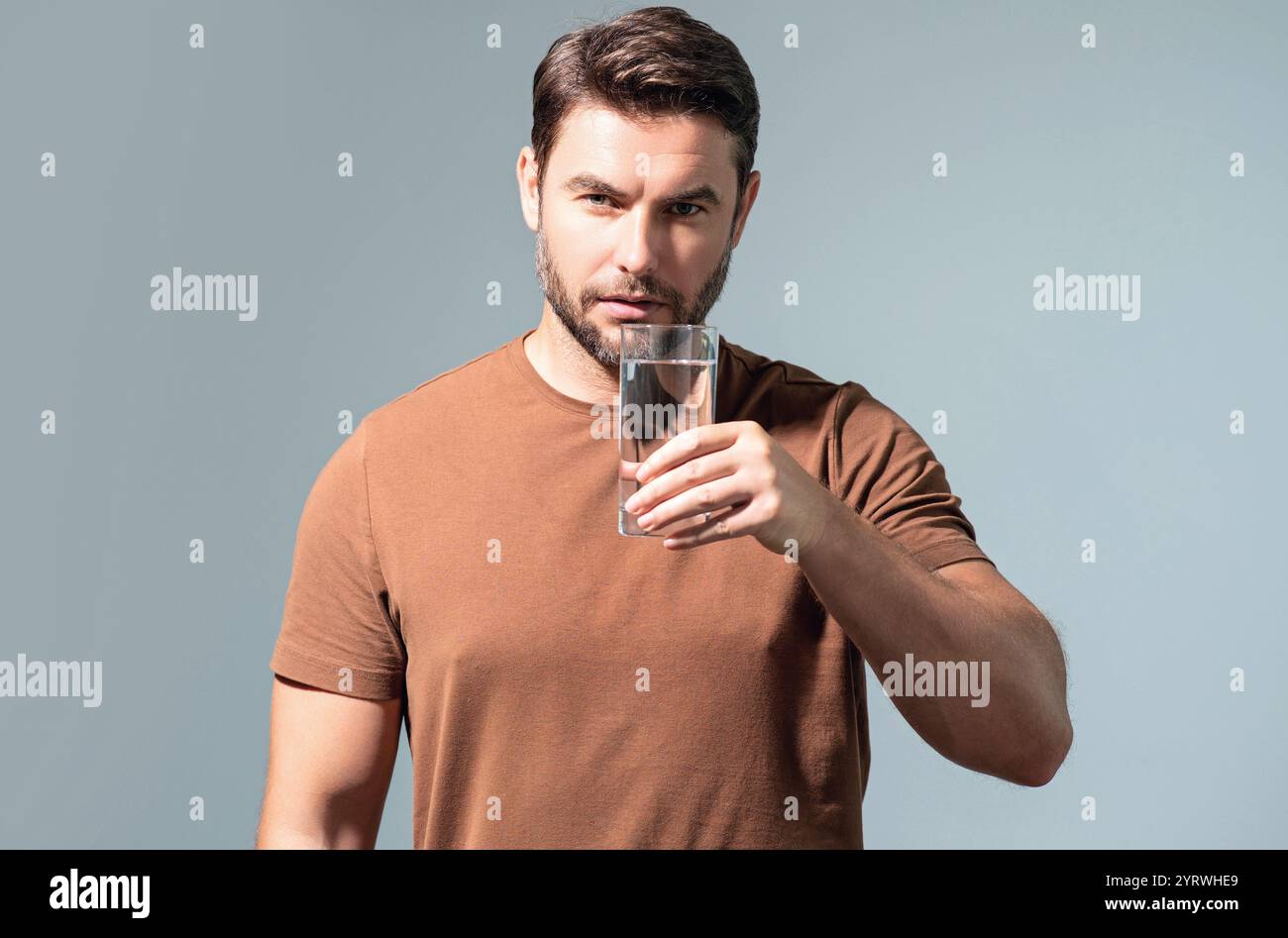 Man drinking a fresh glass of water isolated on studio background ...
