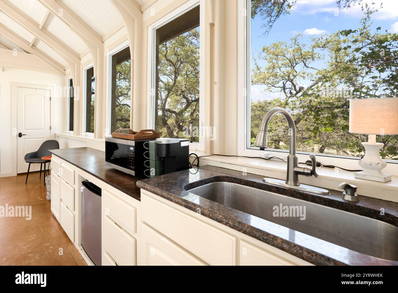 Bright kitchen with large windows overlooking trees in a peaceful ...