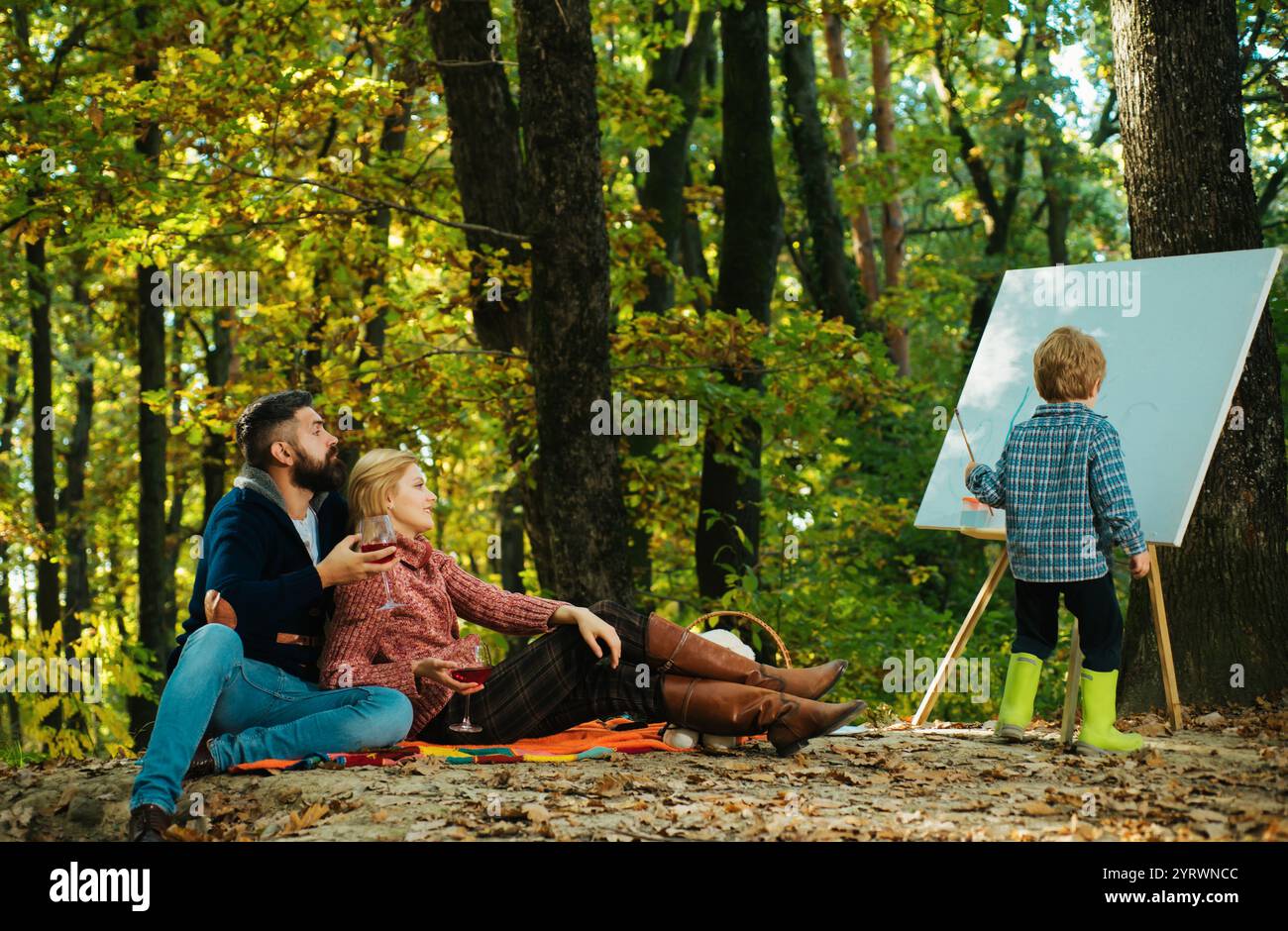 Cute smart son drawing his family giving joyful moments to mom and dad ...