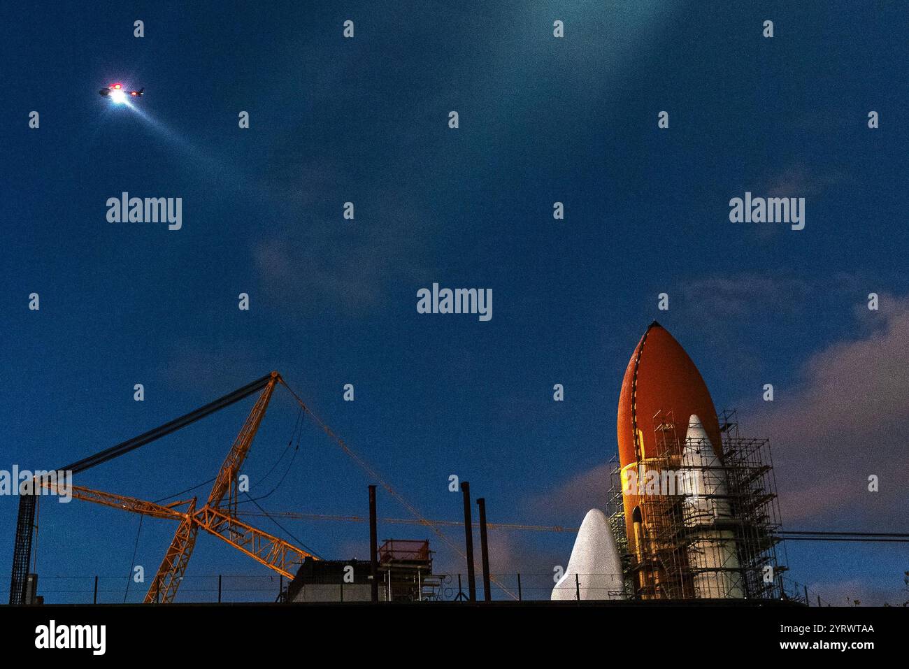A helicopter beams a light on the tip of the fuel tanks of NASA's ...
