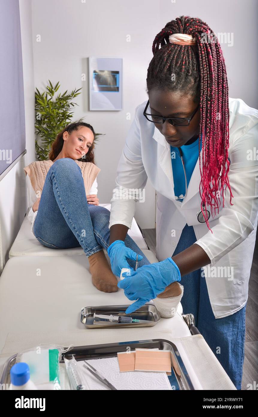 Female doctor bandaging a female patient's foot after giving her an ...