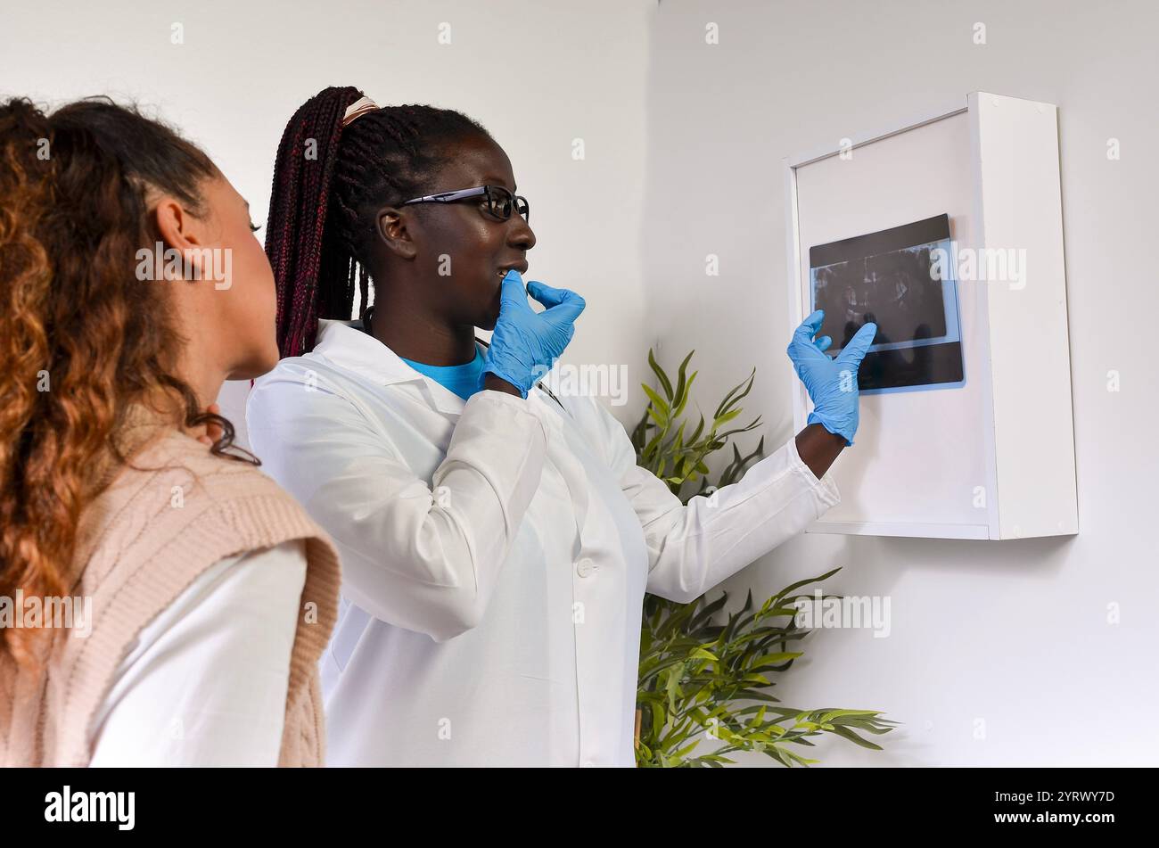 Female doctor wearing lab coat and blue gloves showing radiography ...