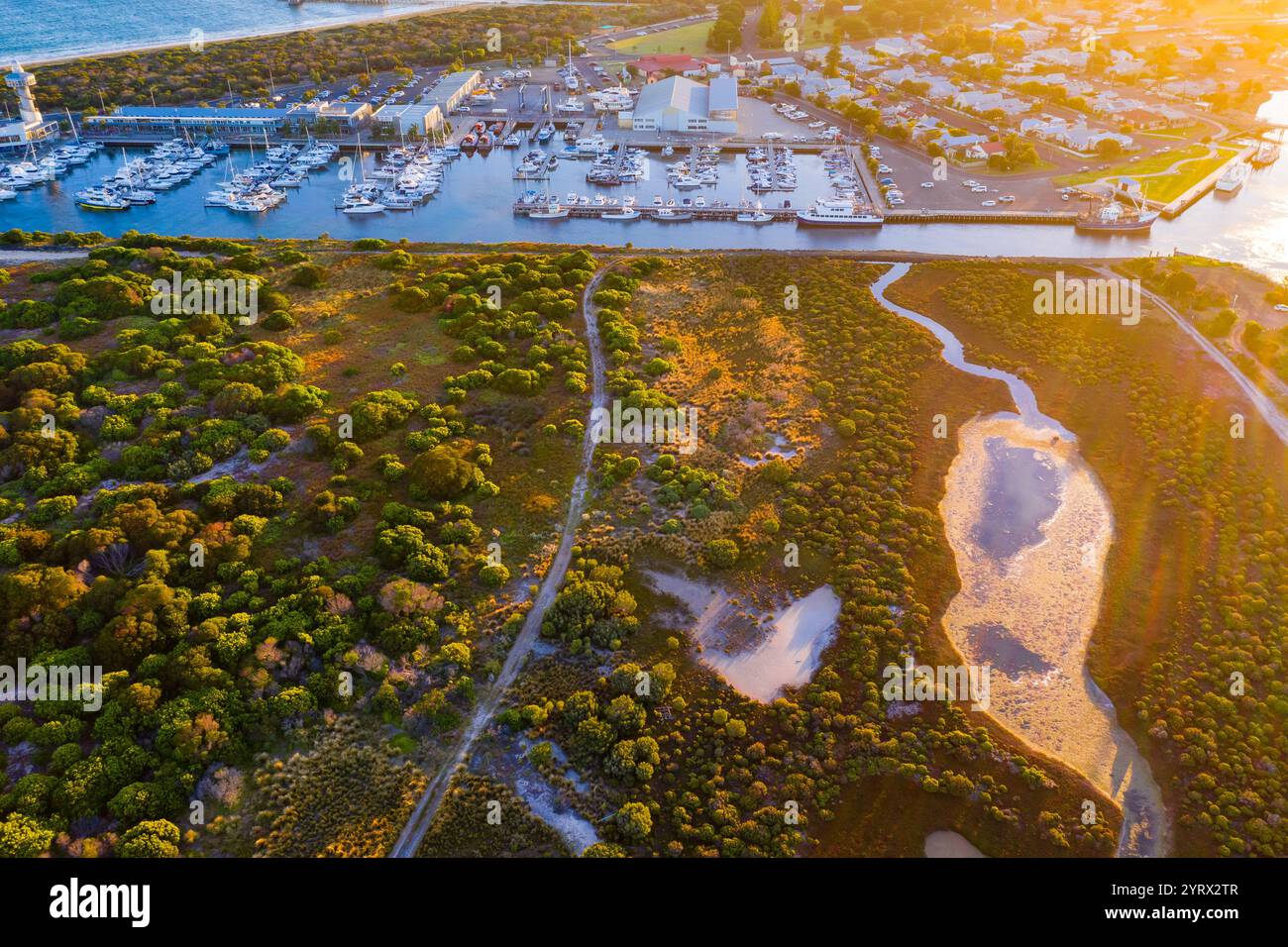 Aerial view of coastal wetlands alongside a boating harbor at ...