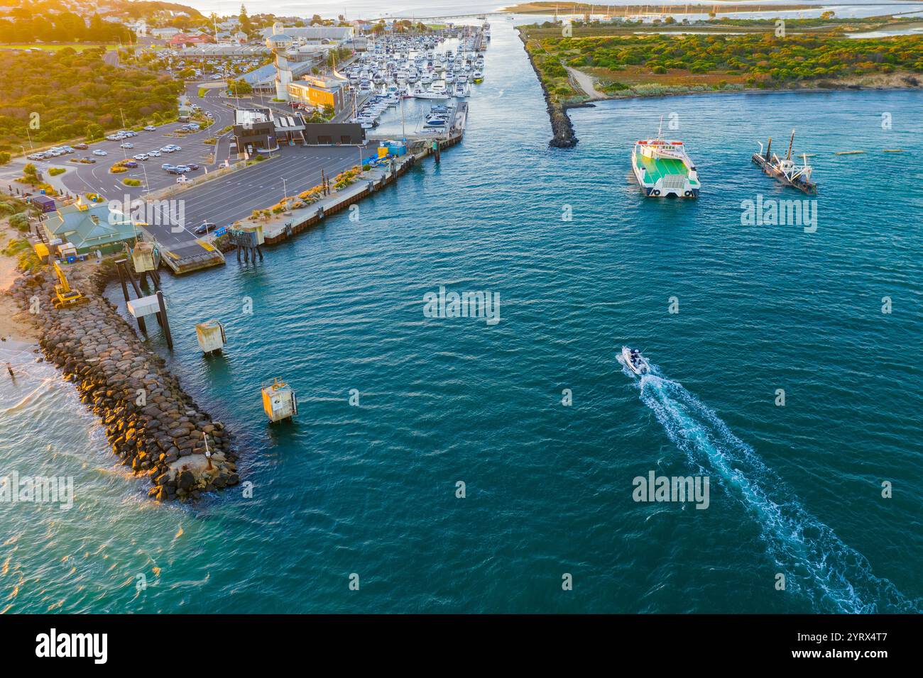 A small boat entering a coastal marina full of boats at anchor at ...