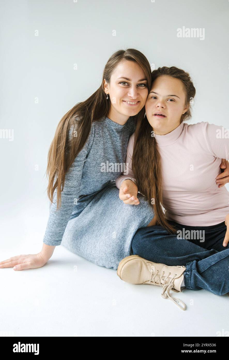 A cheerful mother and daughter with Down syndrome sit together on a ...